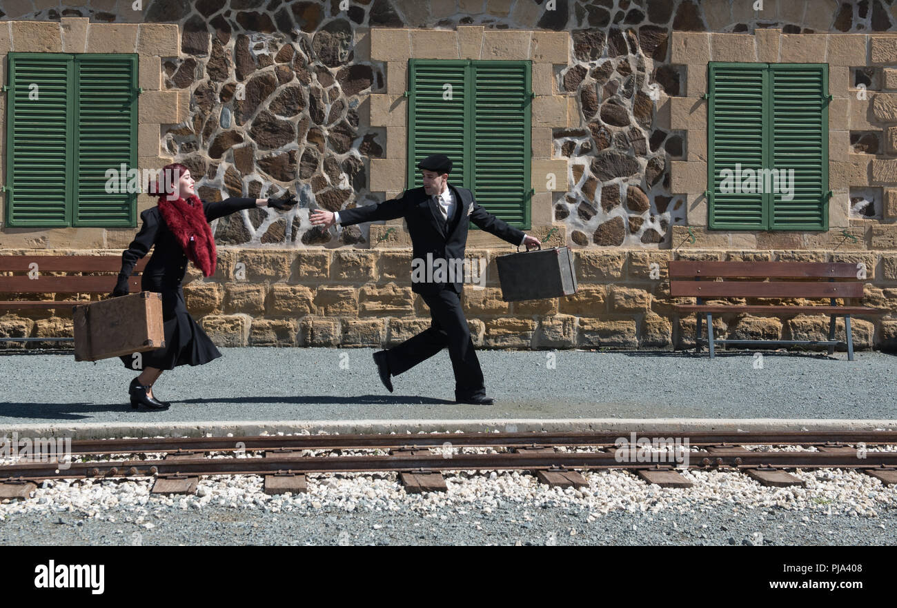 Young couple with vintage suitcase running fast outside a train station ...