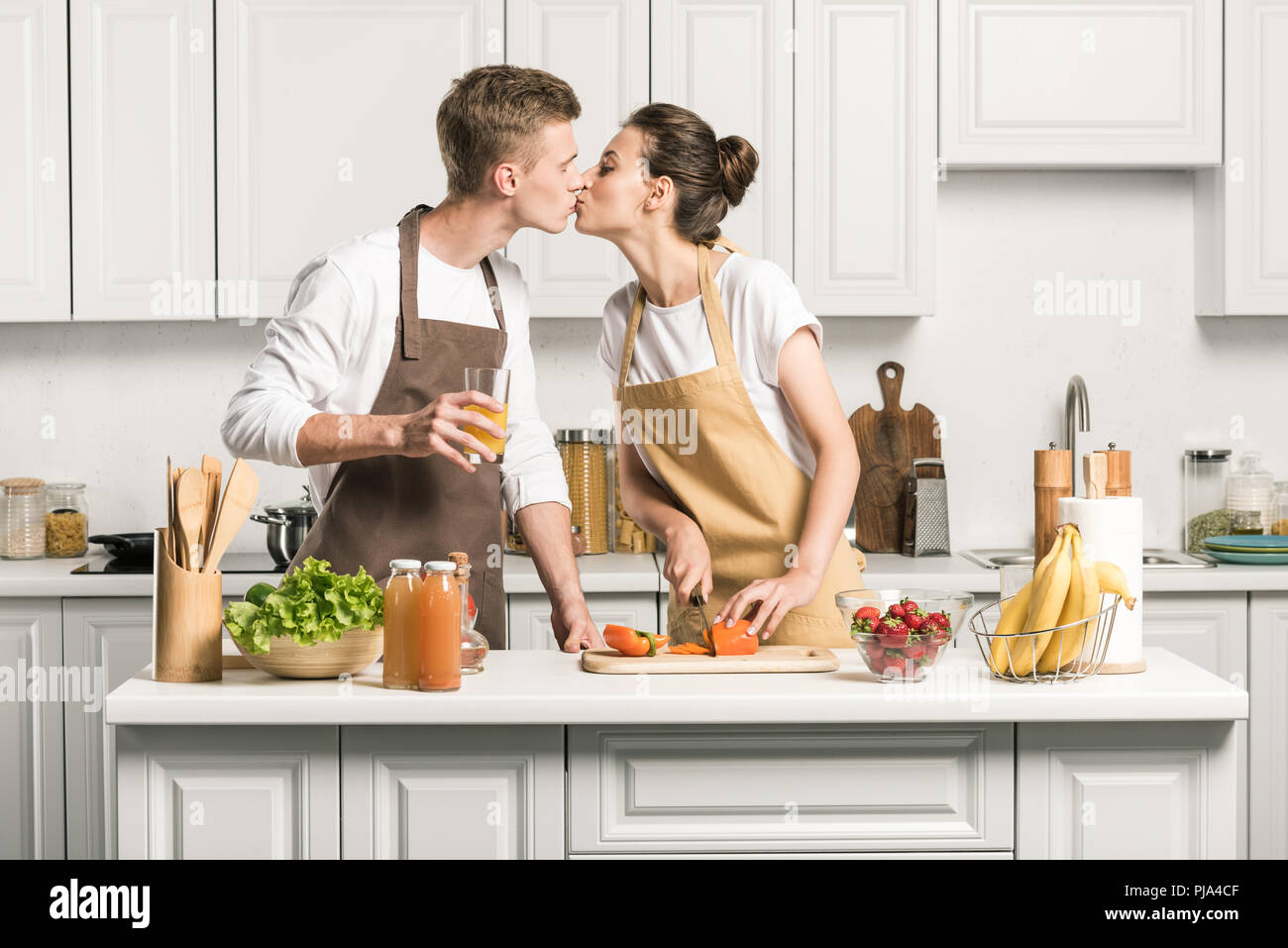 young couple kissing while cooking salad in kitchen Stock Photo - Alamy