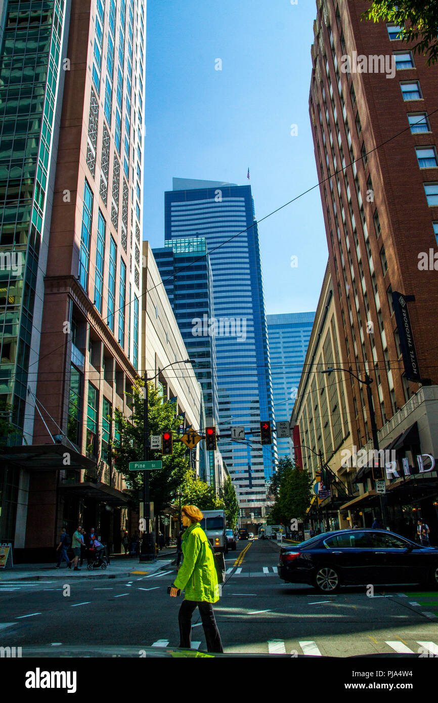 A pedestrian crossing a street among the tall buildings of downtown ...