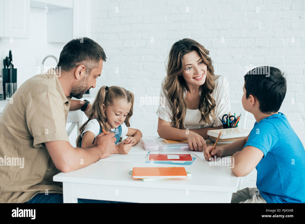 parents helping children with homework at table at home Stock Photo - Alamy