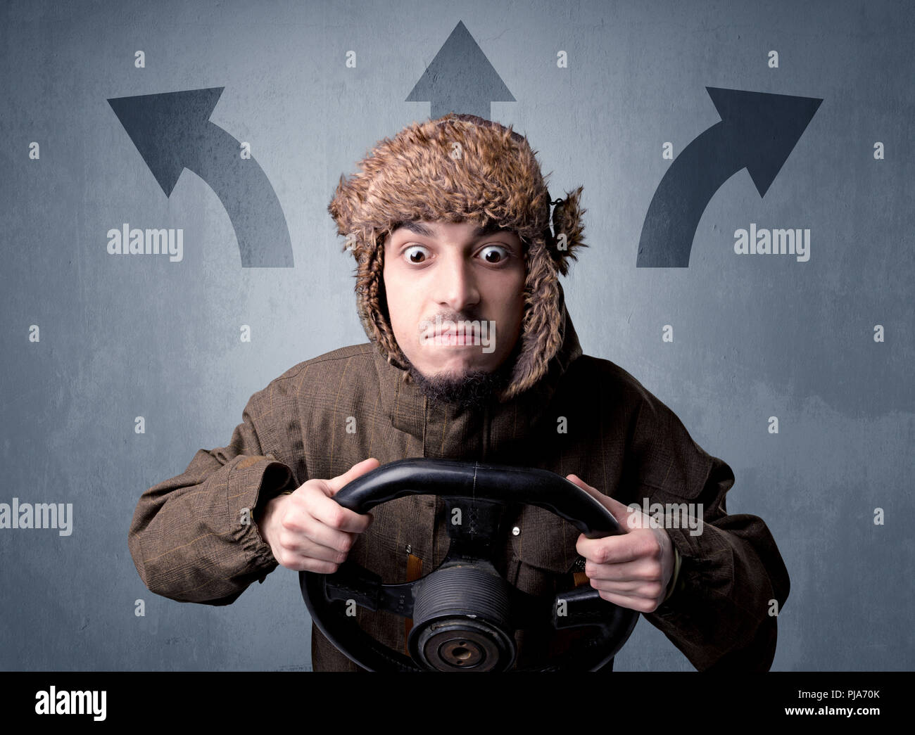 Young man holding black steering wheel with three arrows above his head ...