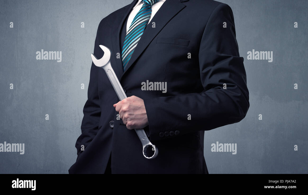 Young, handsome, cute businessman holding tool with grey background ...