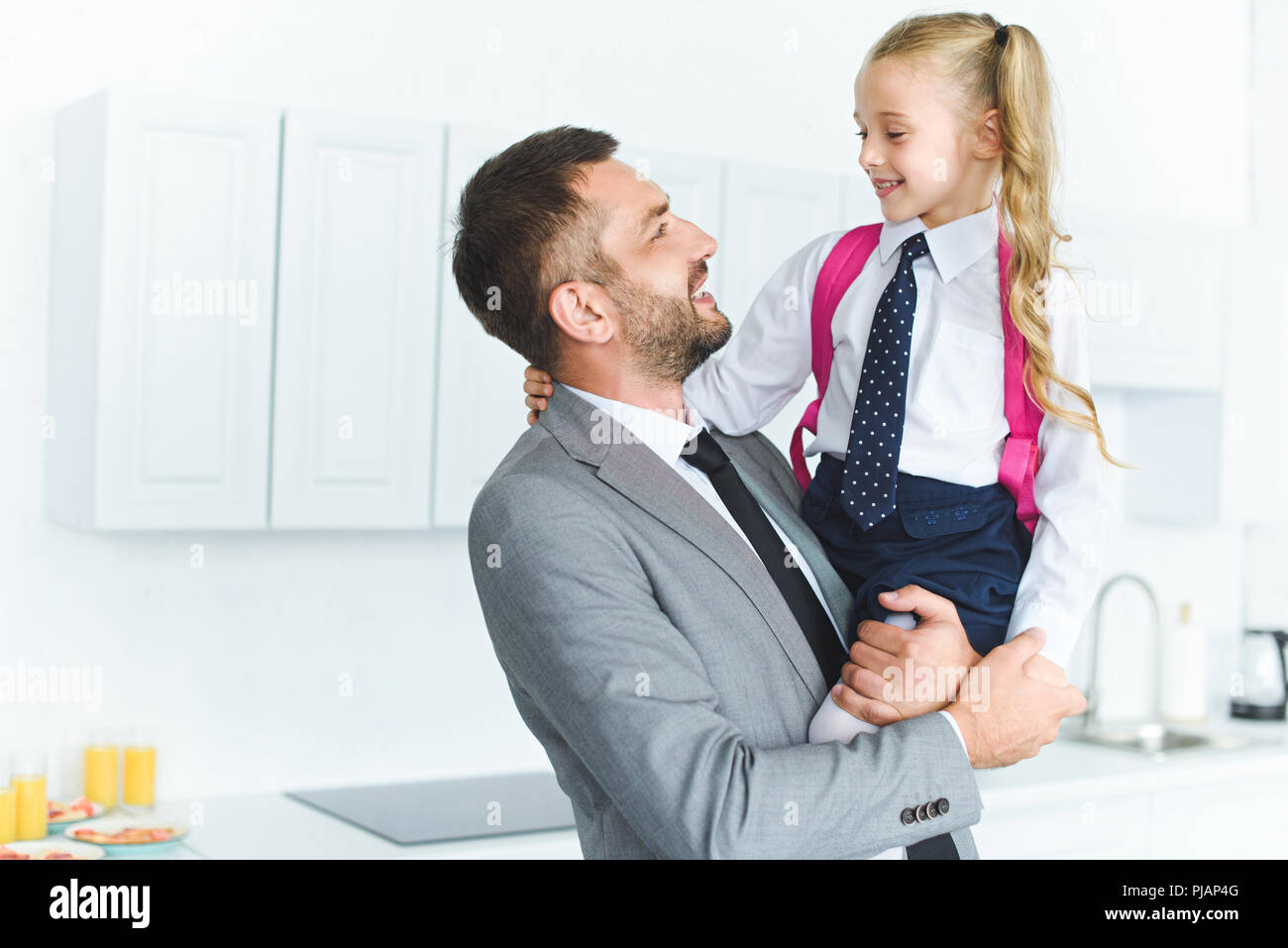 portrait of happy father in suit holding daughter in school uniform ...