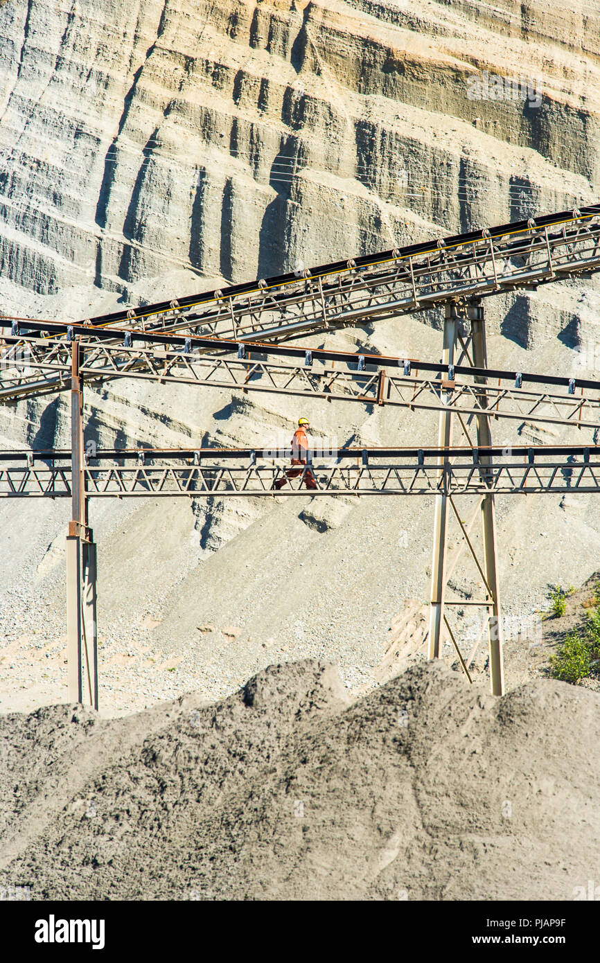 A man walks along a walkway above a gravel pit operation Stock Photo ...