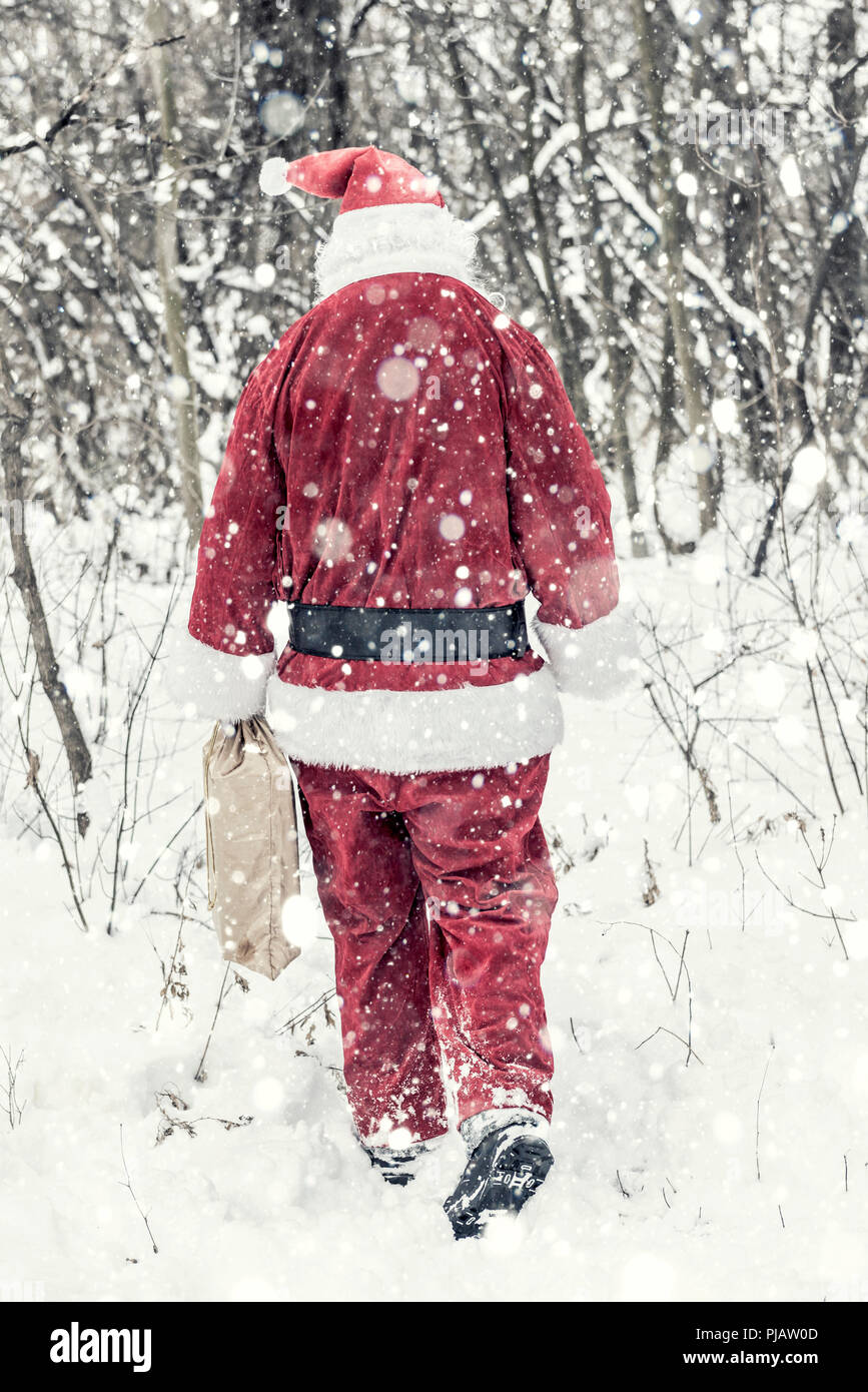 Santa Claus in snow storm holding presents bag Stock Photo - Alamy