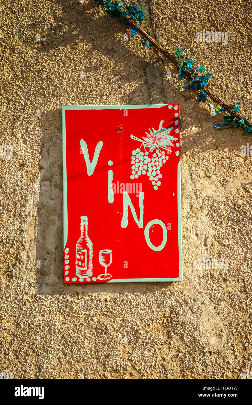Red and white Vino (wine) store sign on the wall in the village of ...