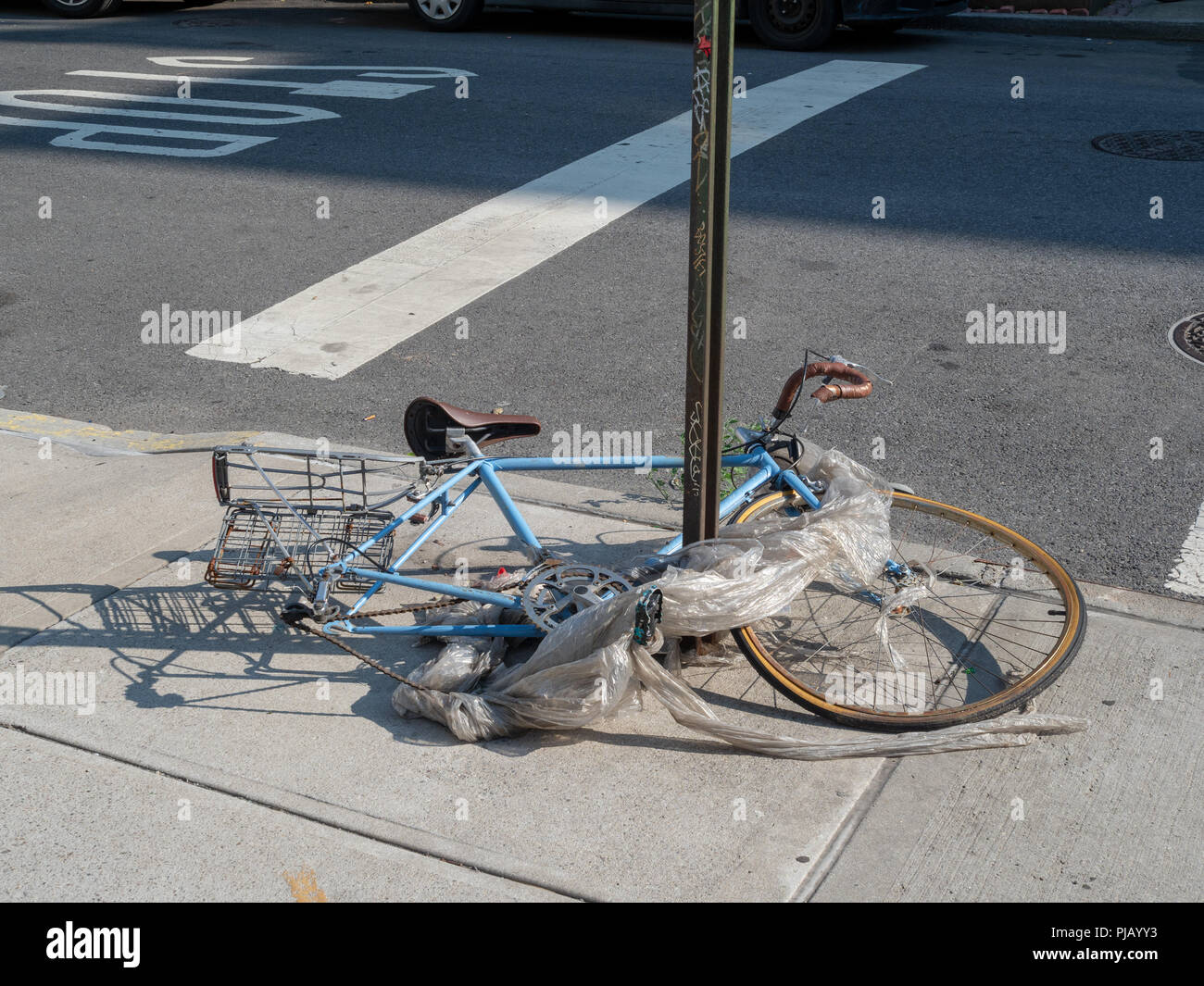 Trashed bike wrapped in garbage broken on street corner Stock Photo - Alamy