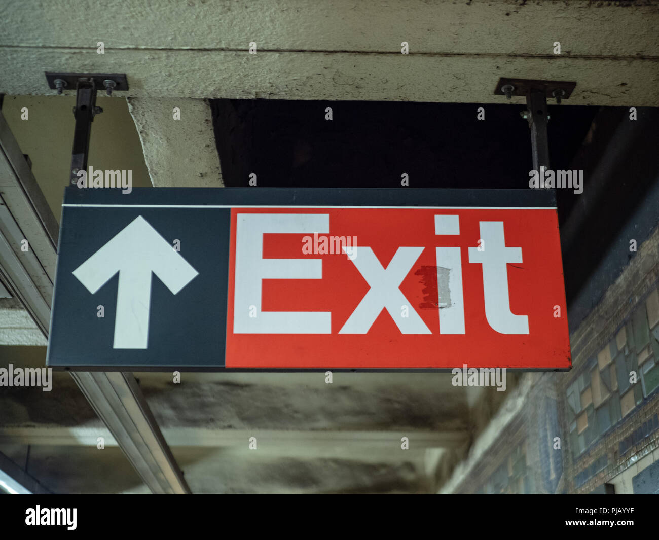 Red exit sign with arrow hanging in underground subway station Stock ...