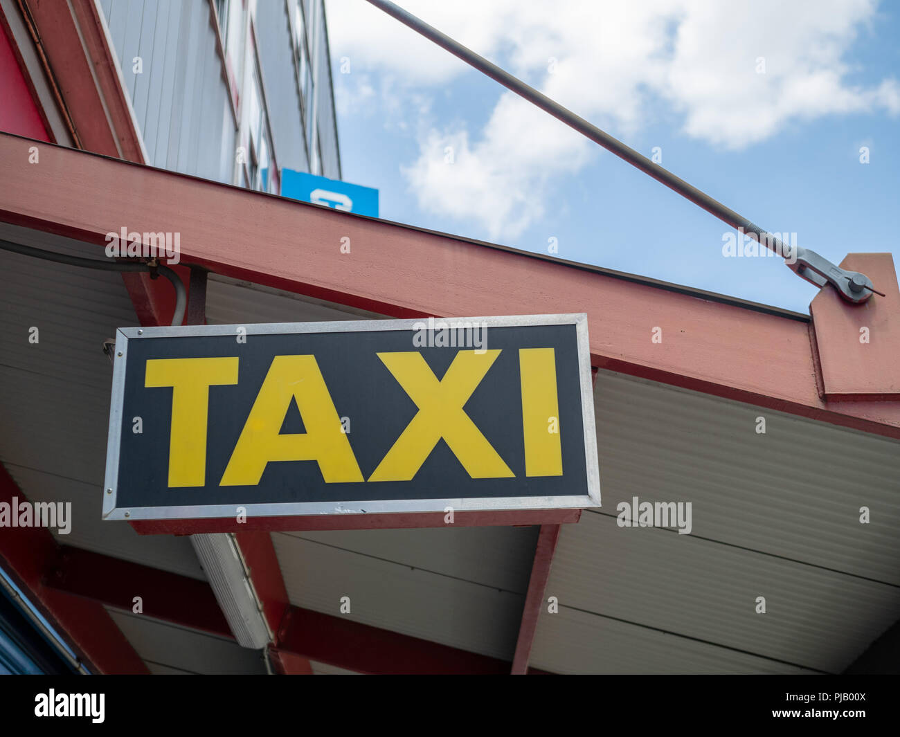 Yellow taxi sign hanging above outdoor waiting area Stock Photo - Alamy