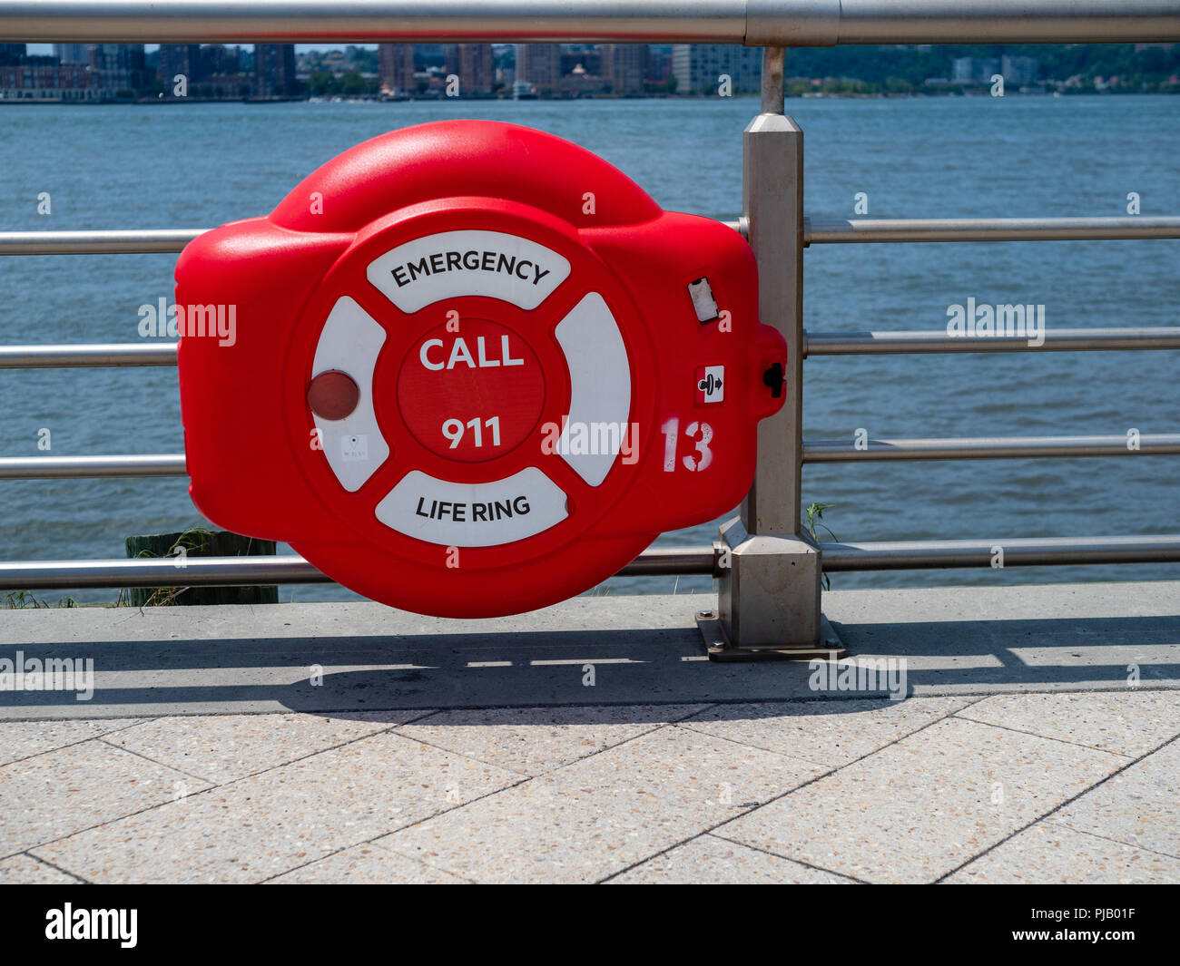 Red emergency life ring hanging on railing next to river Stock Photo ...