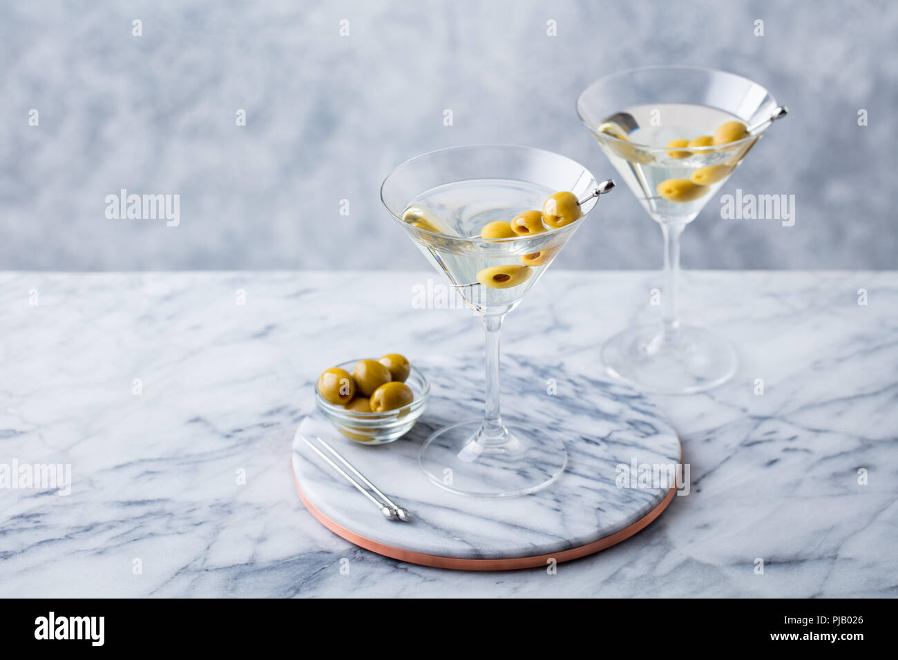 Martini cocktail with green olives on marble table background. Copy ...