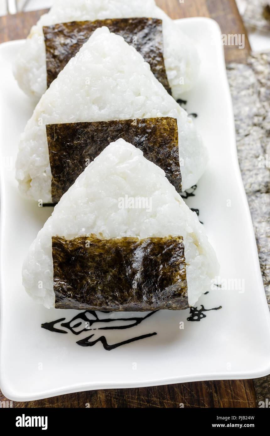 Onigiri. Rice triangle with nori seaweed on white plate Stock Photo - Alamy