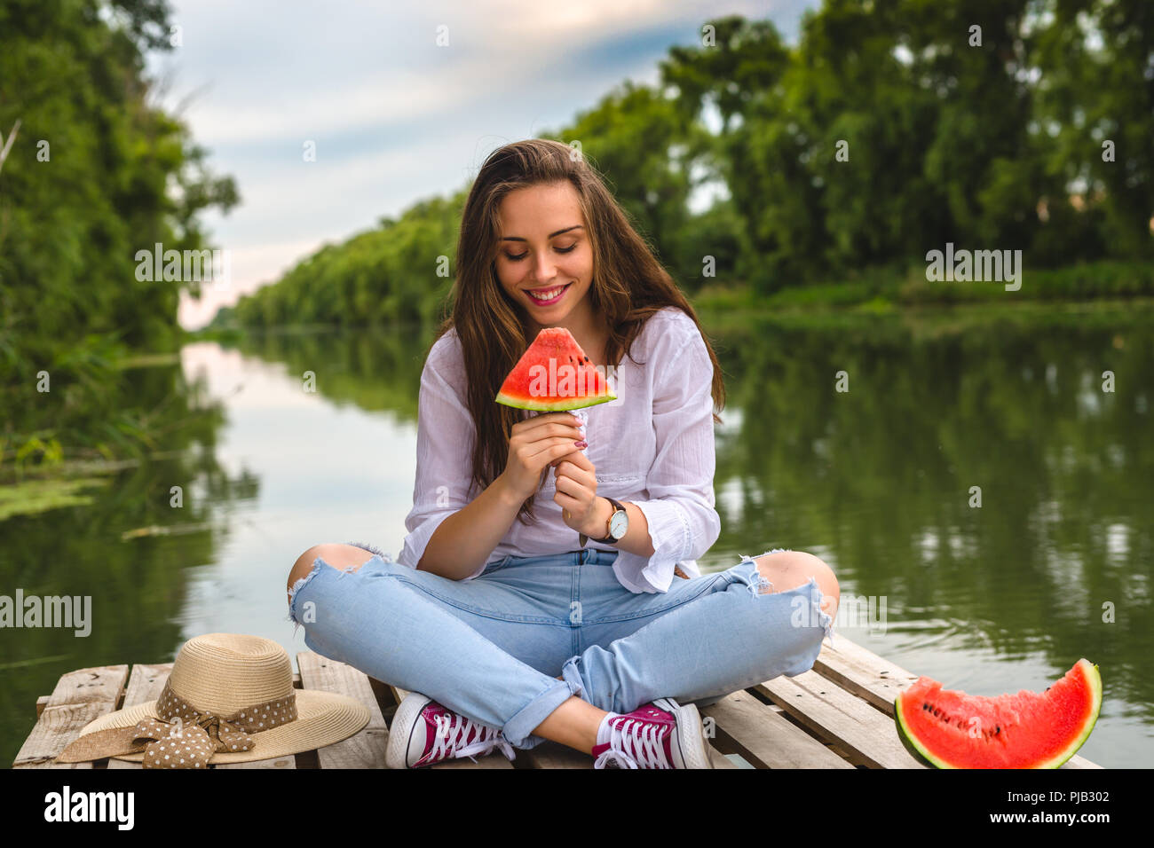 woman outdoor on river dock eating watermelon Stock Photo - Alamy