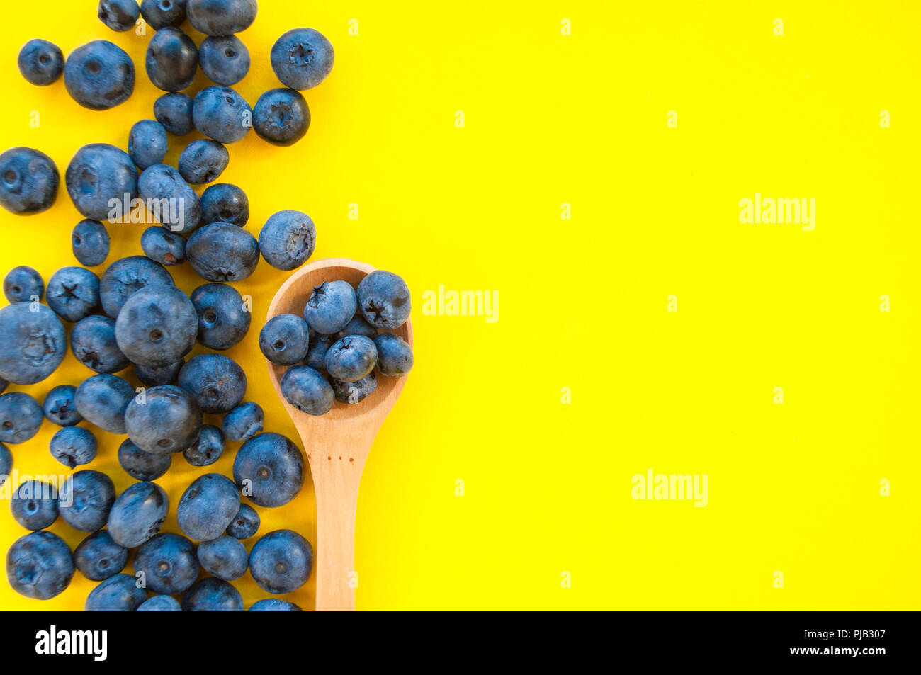 Flat lay of blueberry on bright yellow background Stock Photo - Alamy
