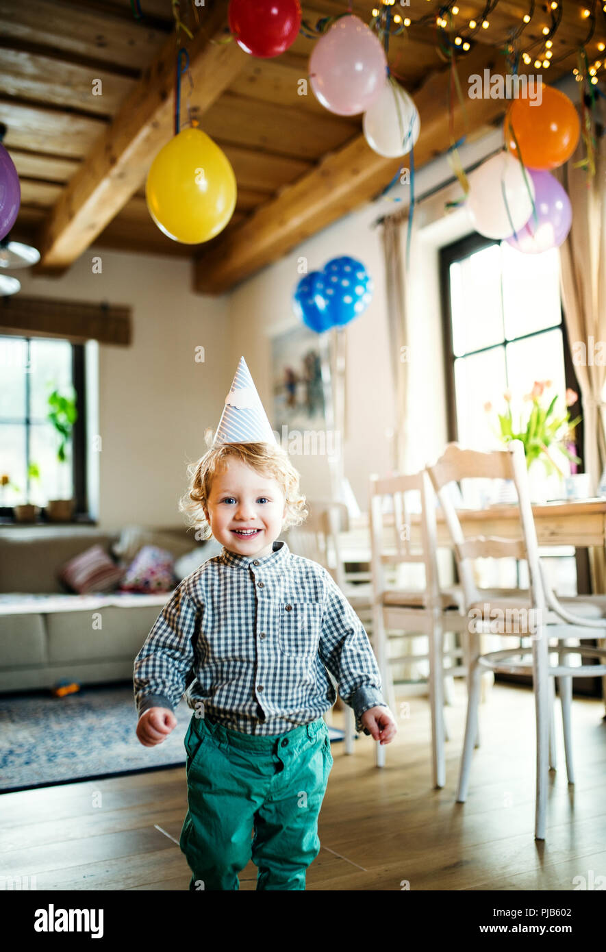 A toddler boy with a party hat walking inside at home Stock Photo - Alamy
