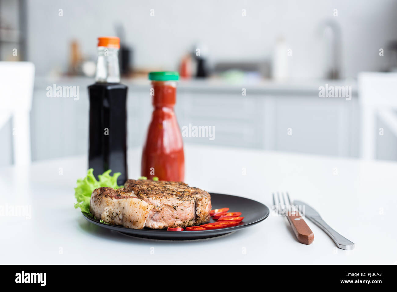 delicious grilled steak, sauces and fork with knife on table Stock ...