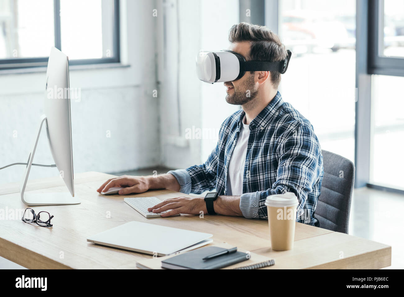 young man in virtual reality headset using desktop computer at ...