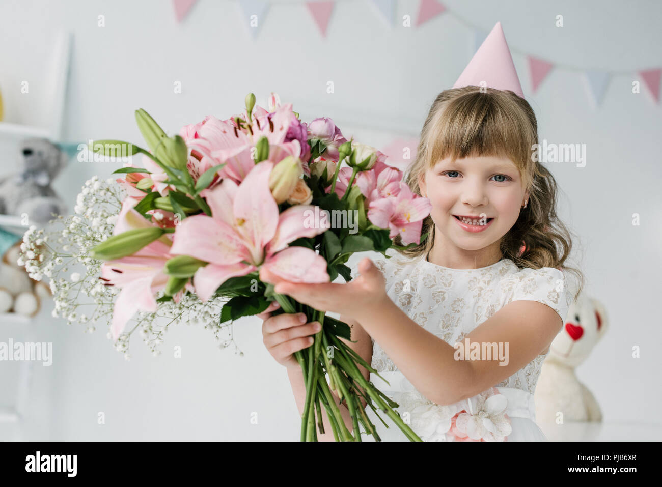 adorable birthday kid in cone showing bouquet of lilies Stock Photo - Alamy