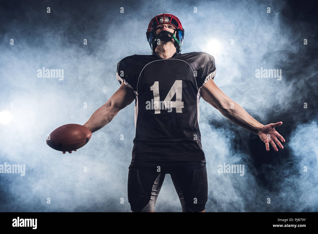 american football player with ball looking up against white smoke Stock ...
