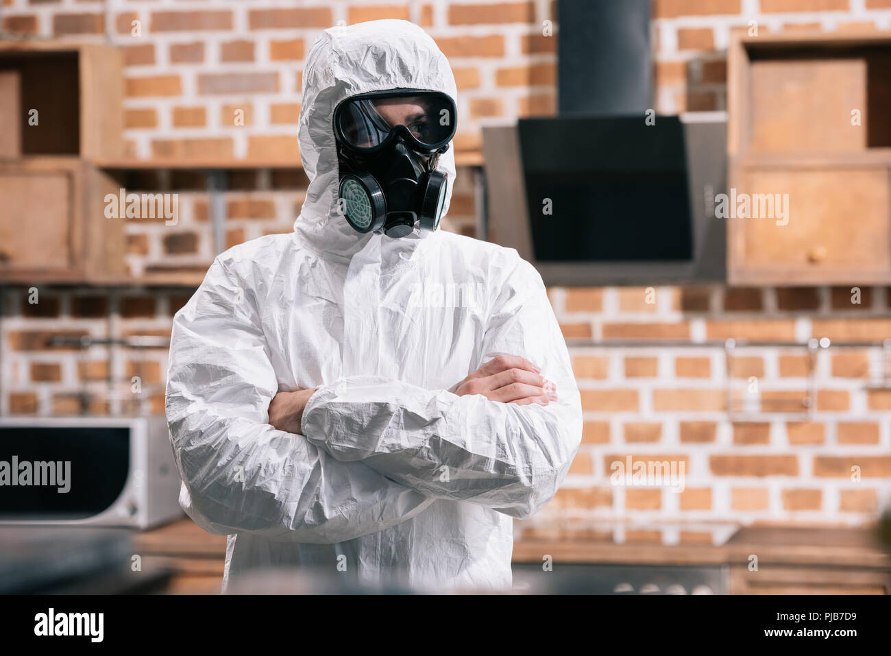 pest control worker standing in uniform with crossed arms in kitchen ...