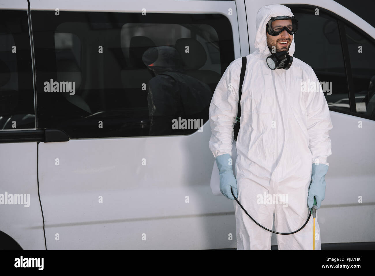 pest control worker in uniform standing near car on street and holding ...