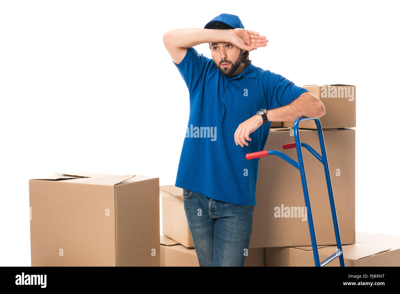 tired delivery man standing between cardboard boxes and looking away ...