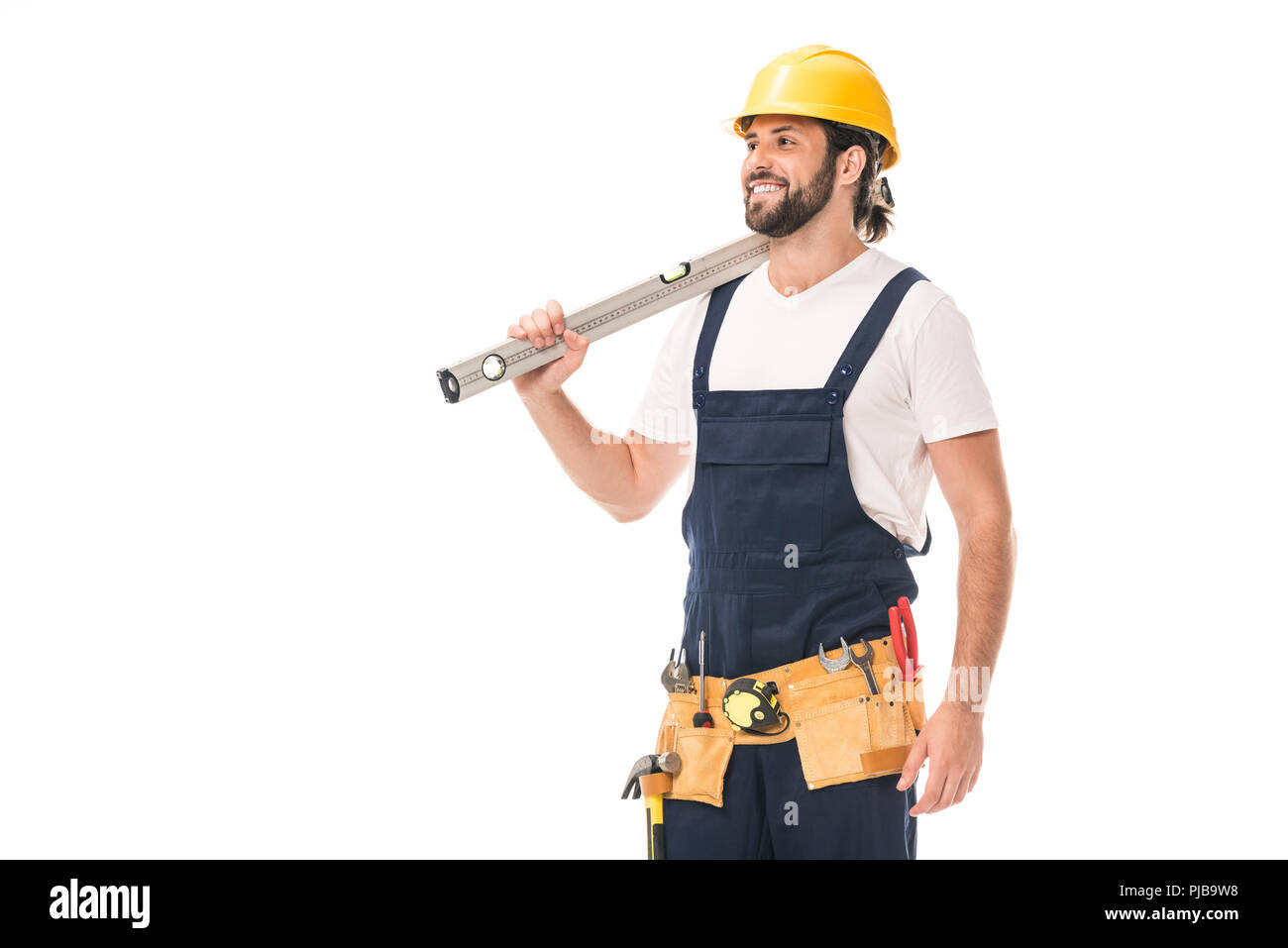 happy handsome workman holding level tool and looking away isolated on ...