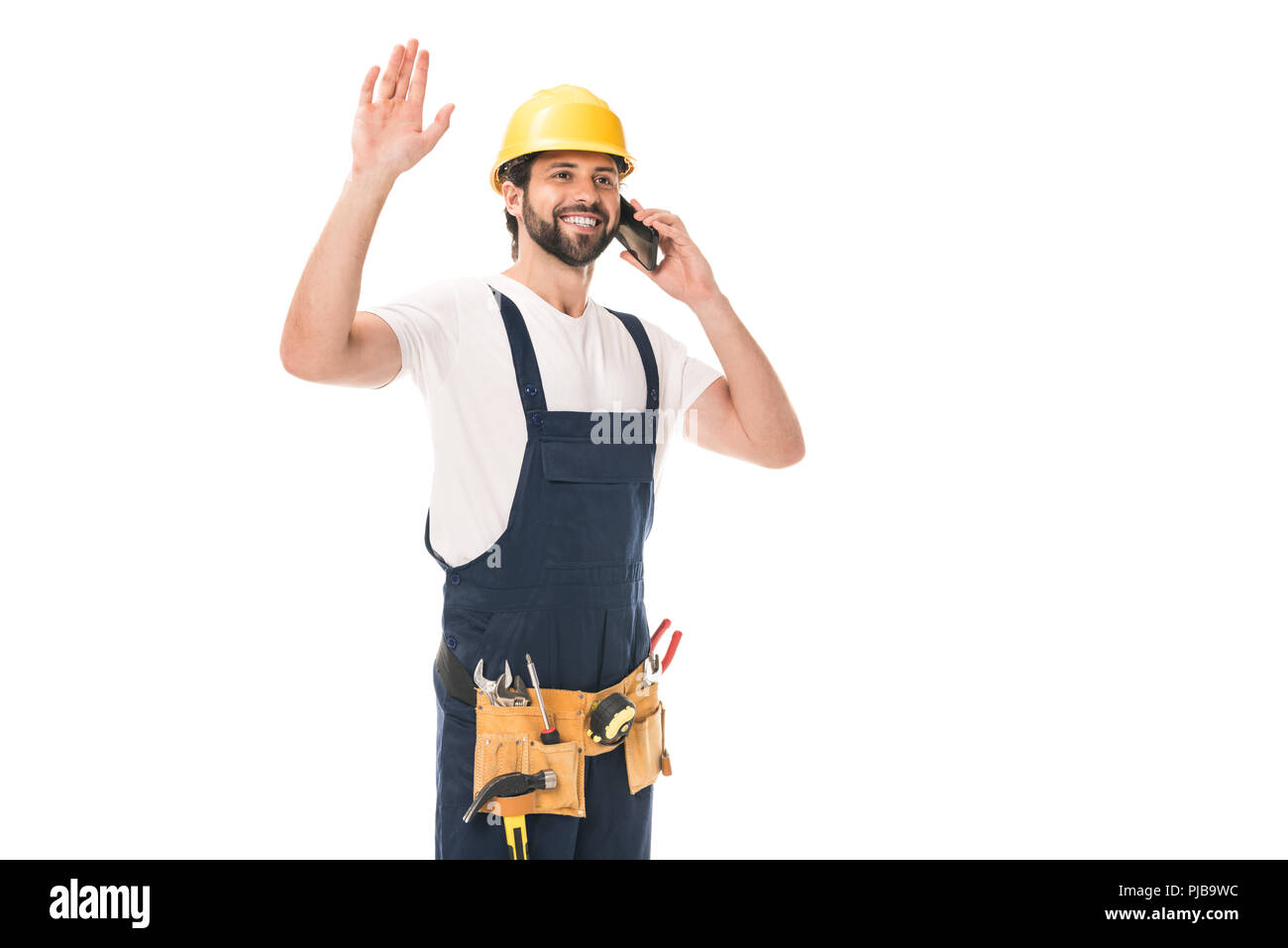 cheerful construction worker talking by smartphone and waving hand ...