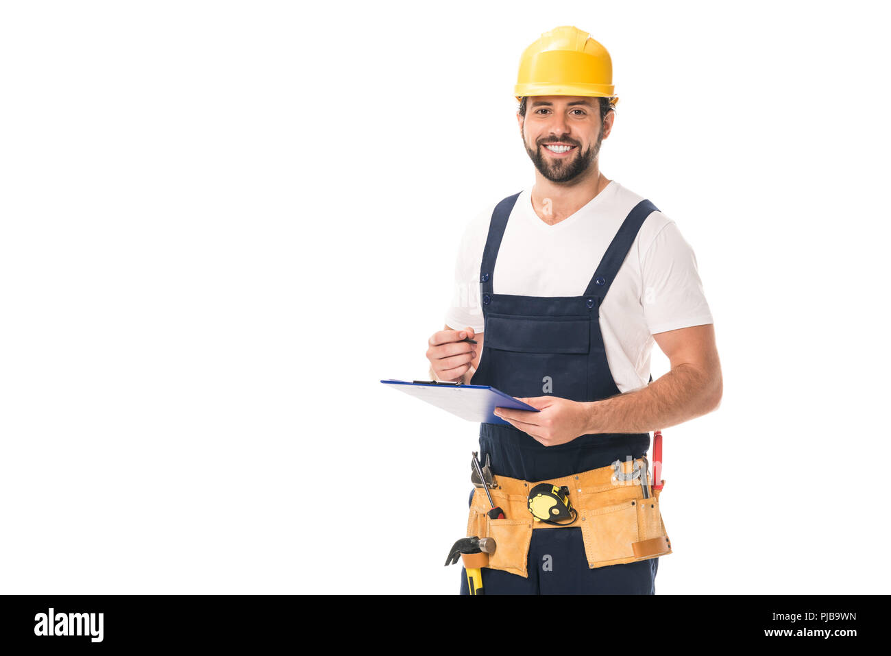 handsome happy workman in tool belt and hard hat writing on clipboard ...