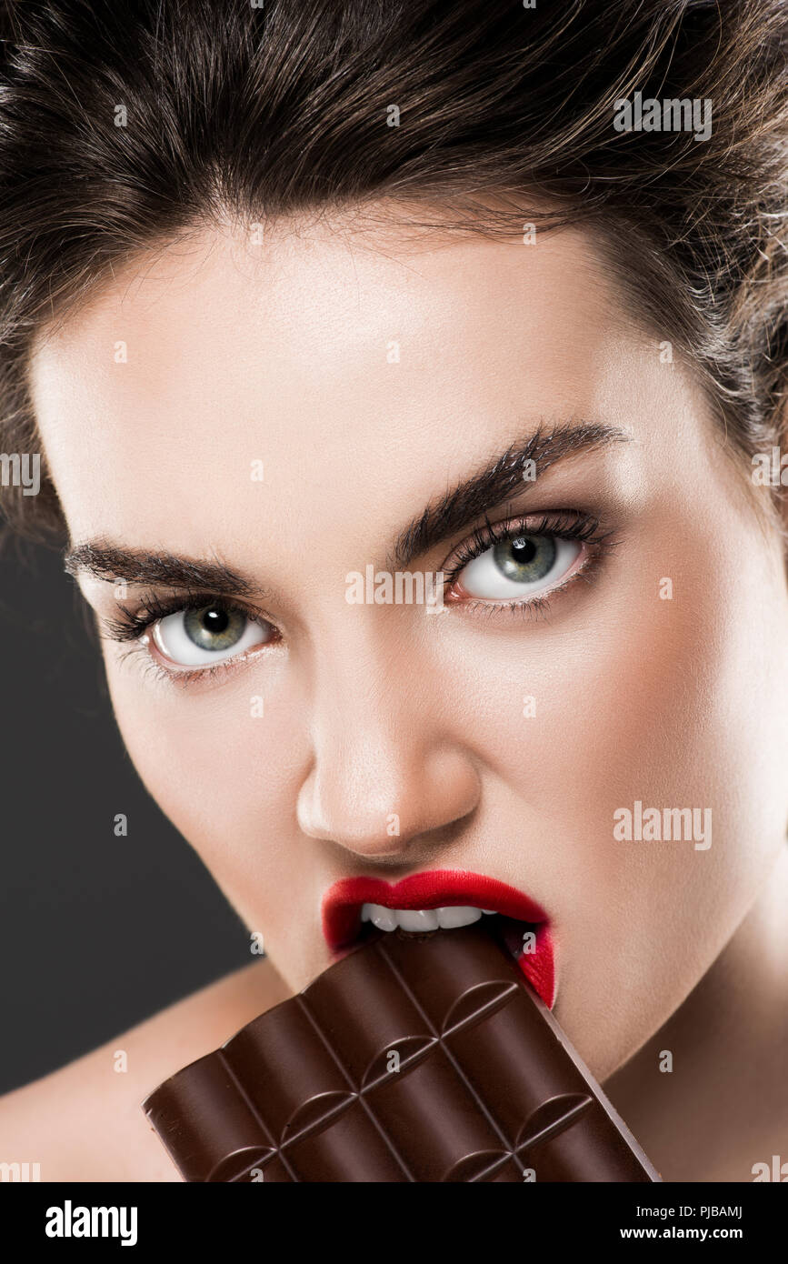beautiful fashionable woman biting chocolate bar, isolated on grey ...
