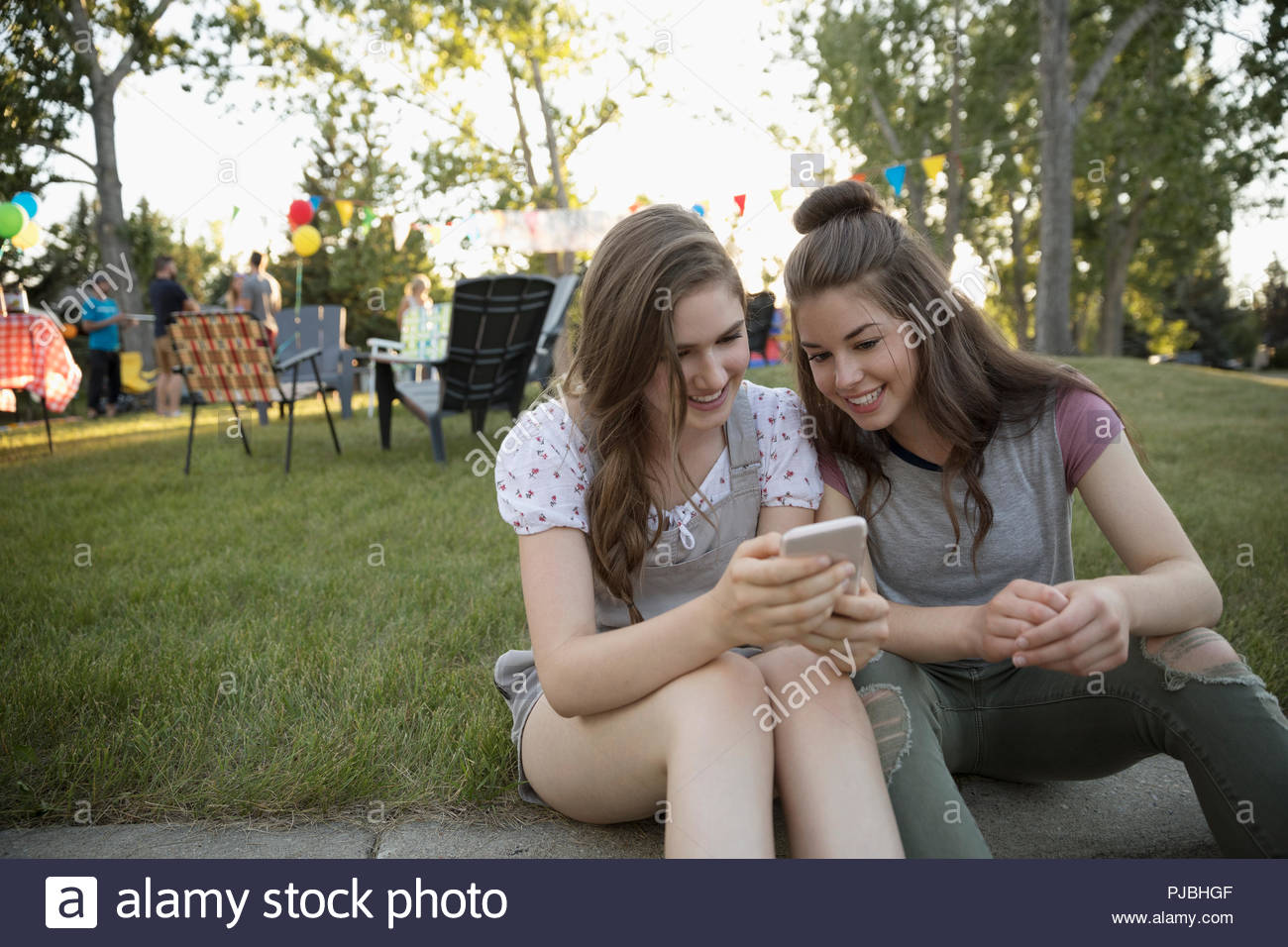 Teenage girl friends with smart phone at summer neighborhood block ...