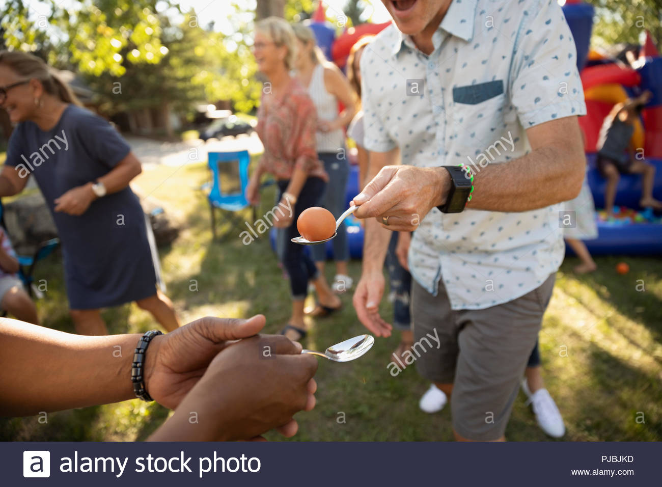 Neighbors enjoying egg and spoon race at summer neighborhood block ...