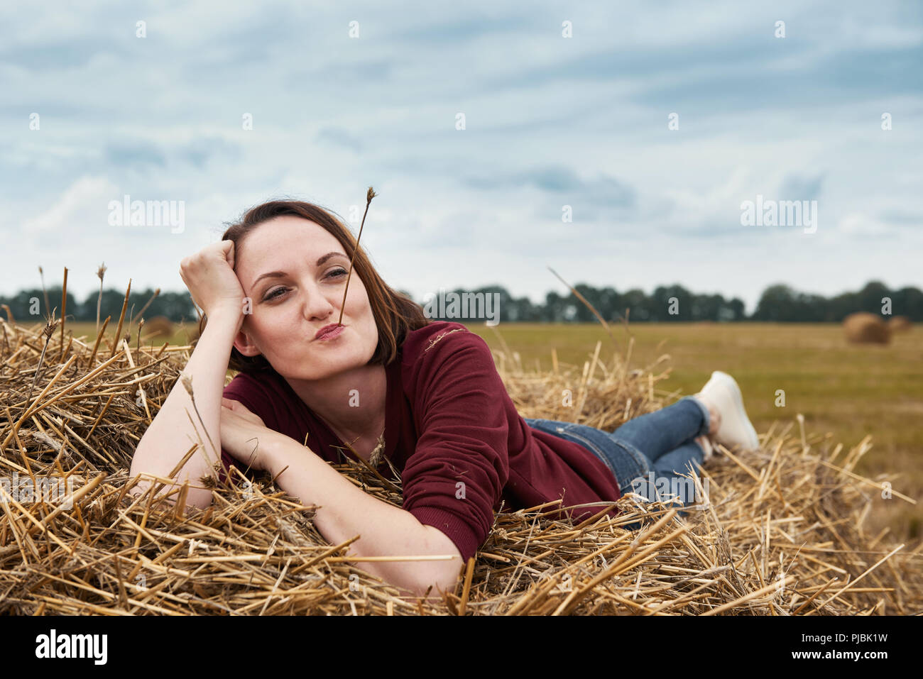 young girl having fun in the field, lying on a haystack Stock Photo - Alamy