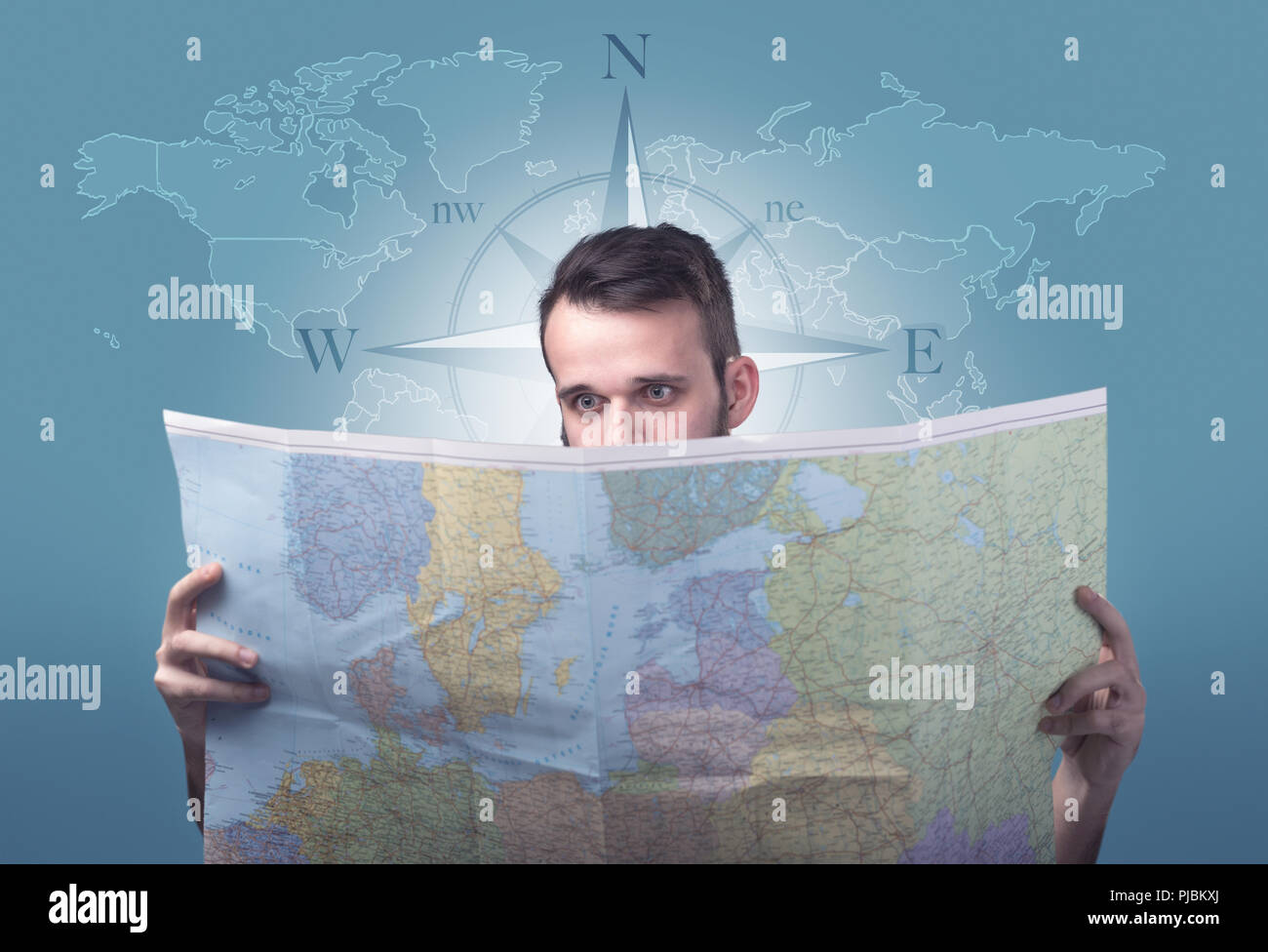 Handsome young man holding a map with a world map and a compass behind ...
