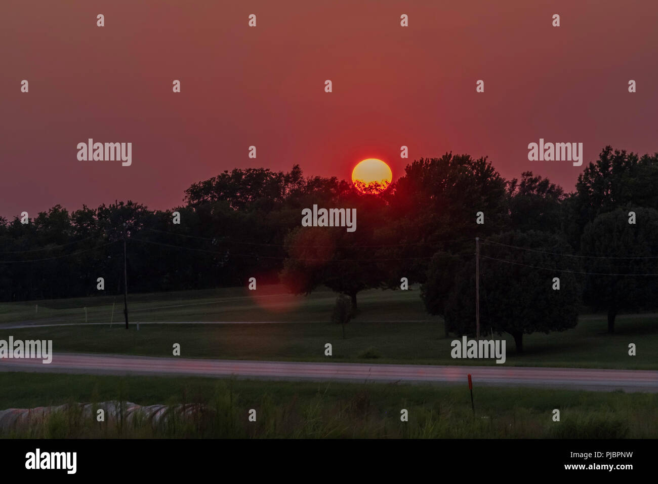Orange ball of sun setting in the Oklahoma, USA countryside. Glowing ...