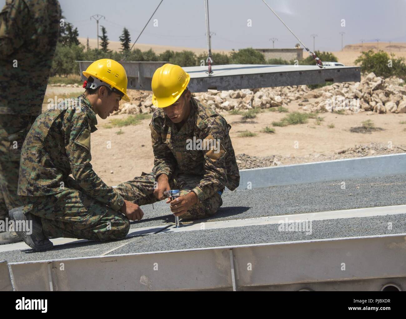 Two Syrian Democratic Forces engineers work together to tighten and ...