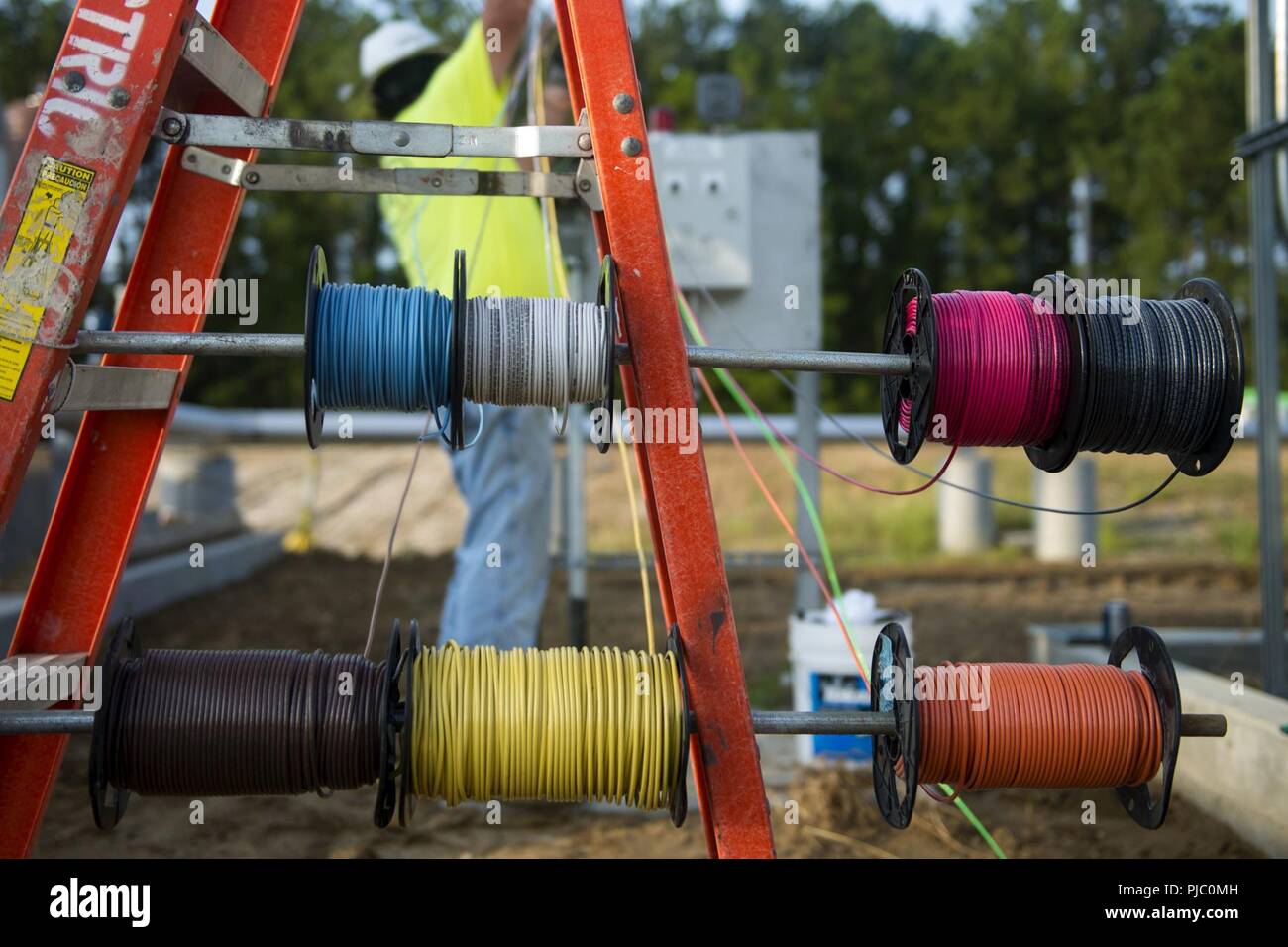 A worker spools conductor wire to a safety switch in the 23d Logistics ...