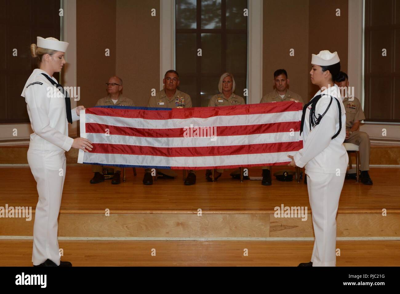 Sailors unfold the ceremonial flag during Master Chief James Baker's ...