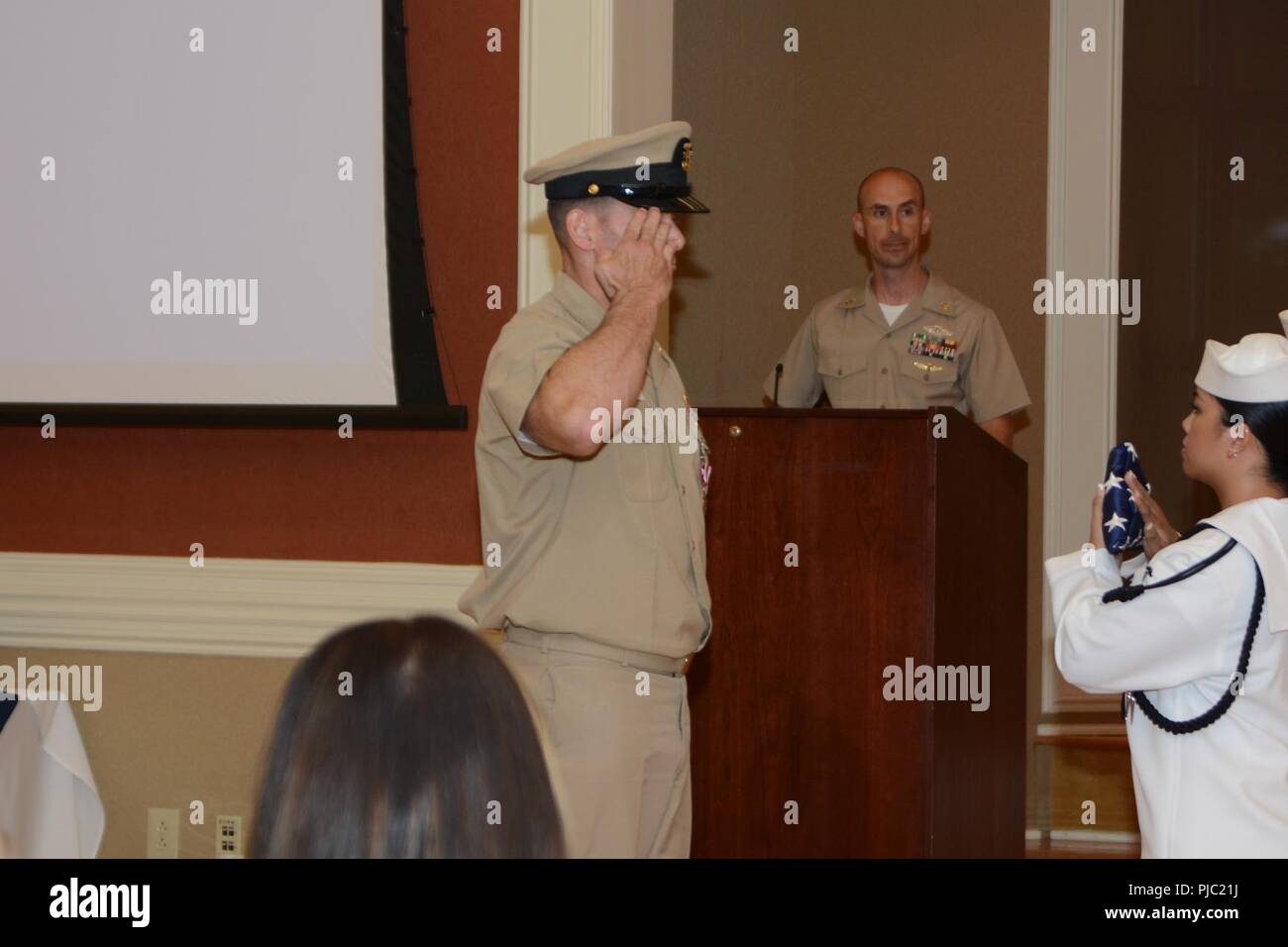 Master Chief James Baker salutes the folded ceremonial flag during his ...