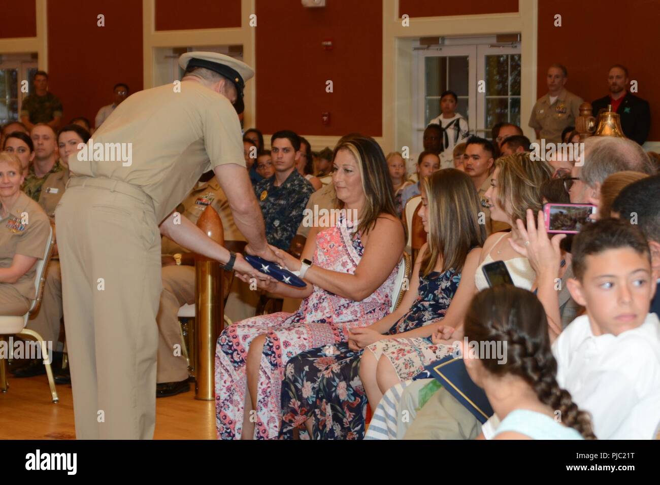 Master Chief James Baker presents a folded flag to his wife during his ...