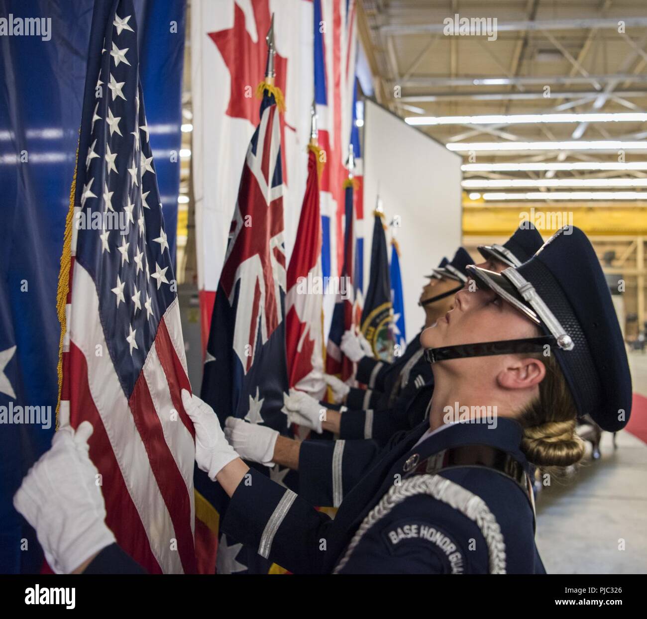 A U.S. Air Force honor guard straightens the flags of the four nations ...