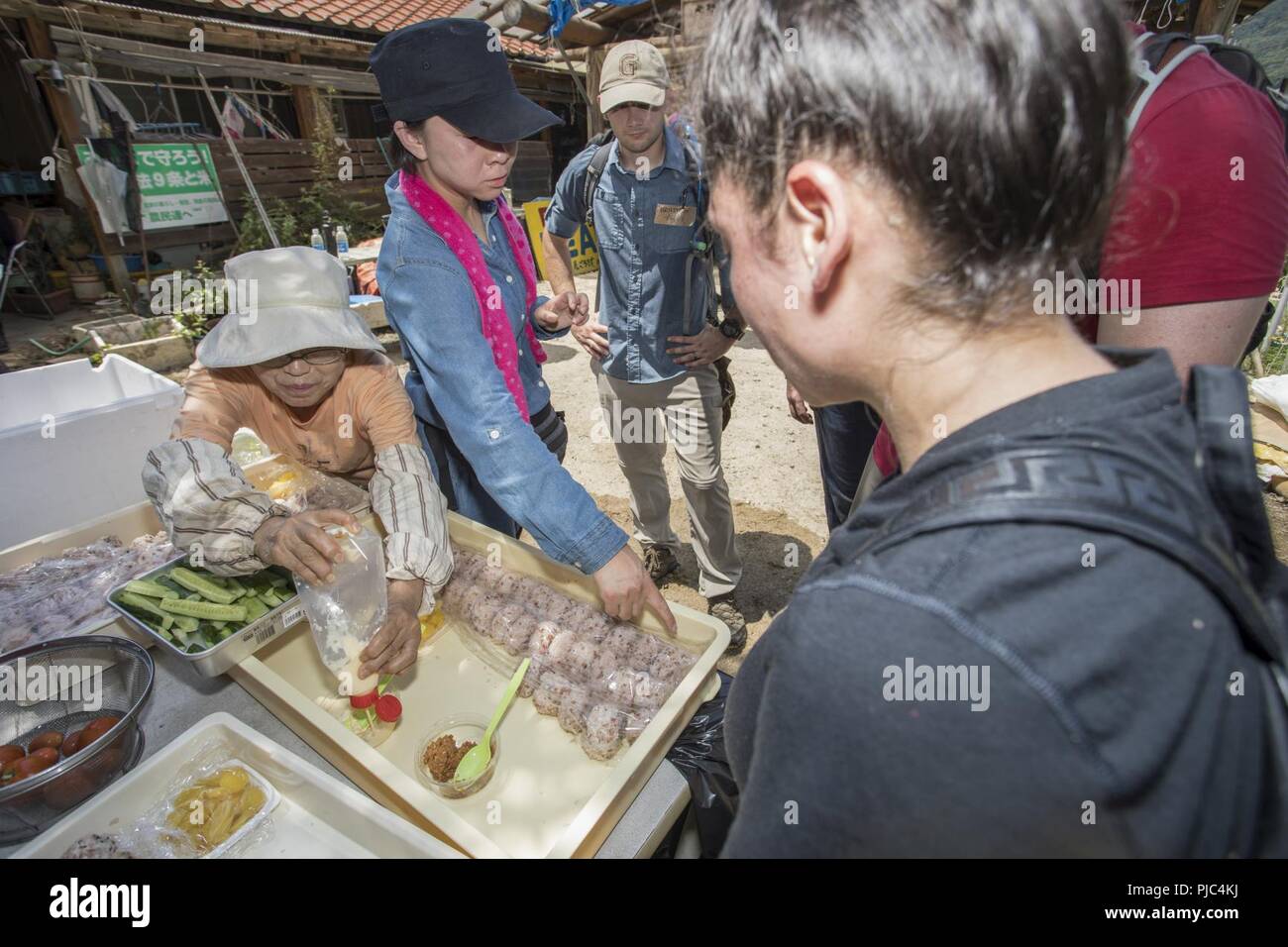A Japanese local squeezes a condiment into a dish for volunteers from ...