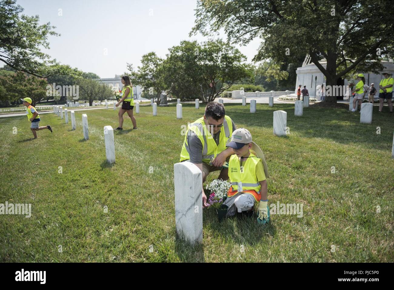 Jason Jordan helps his son, Jace, place flowers at a gravesite next to ...