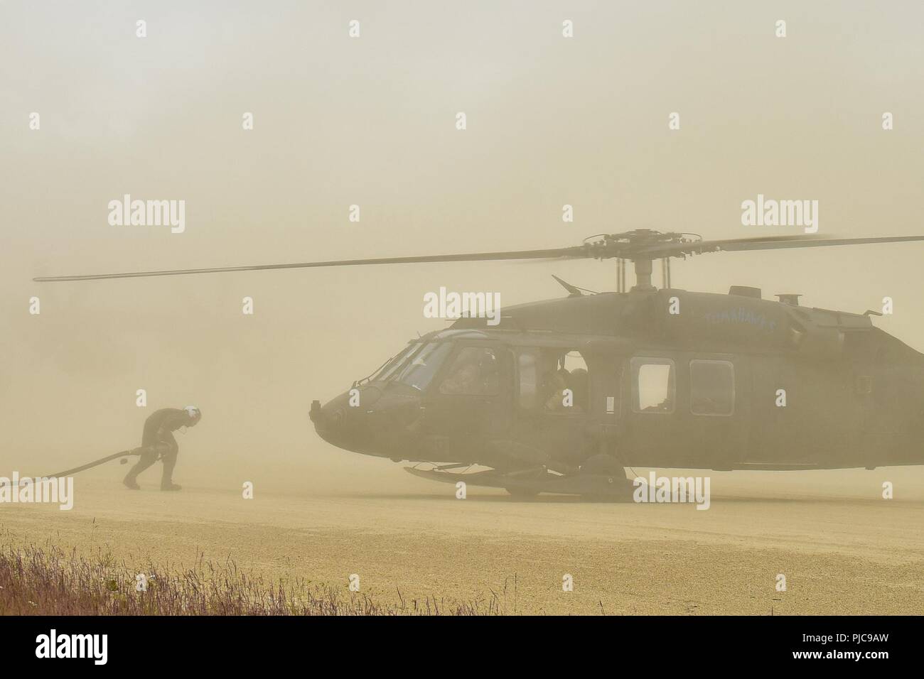 A Marine prepares to refuel an Army UH-60 Black Hawk from a USMC C-130 ...