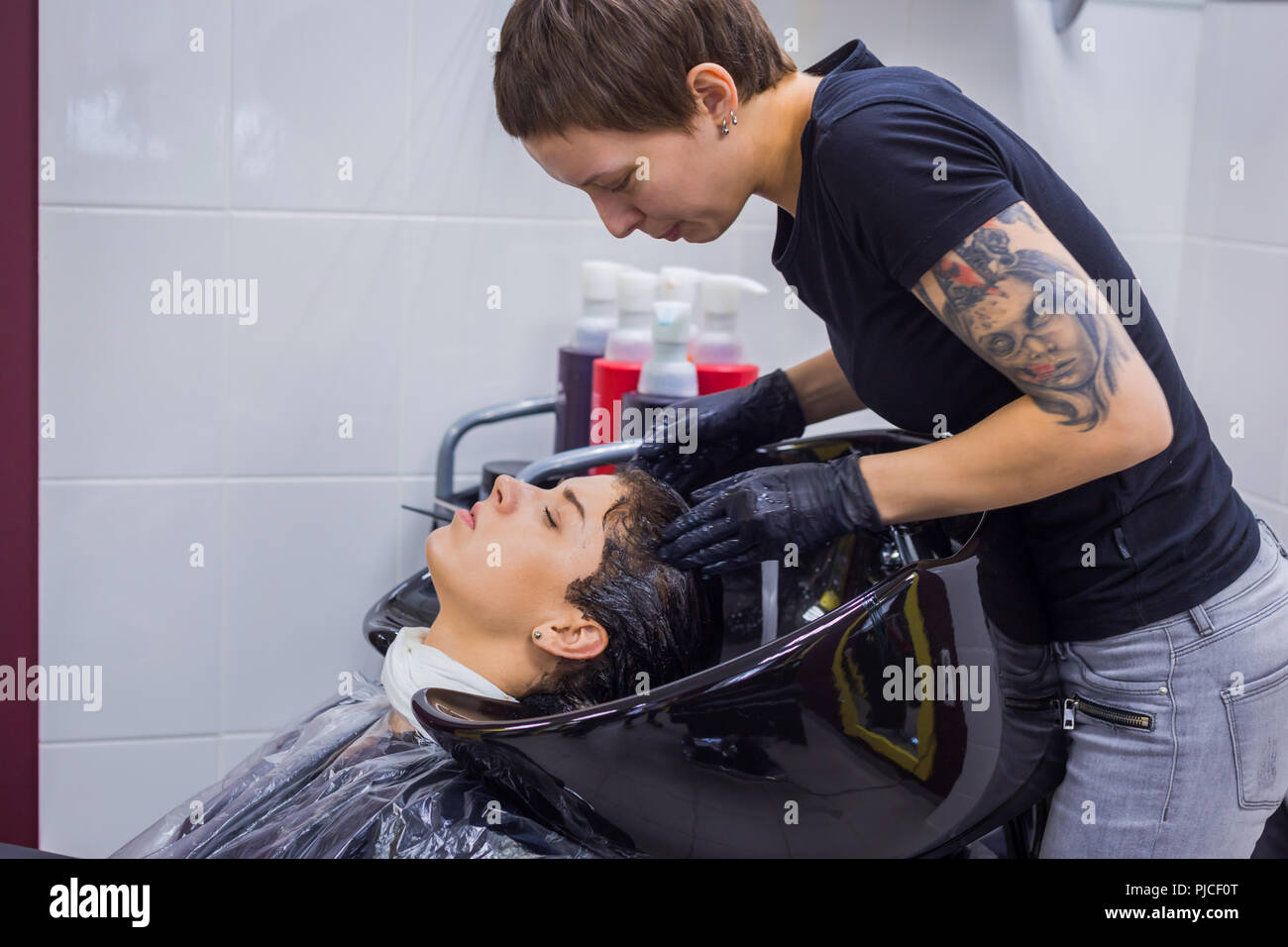 Hairdresser washing hair of woman client Stock Photo - Alamy