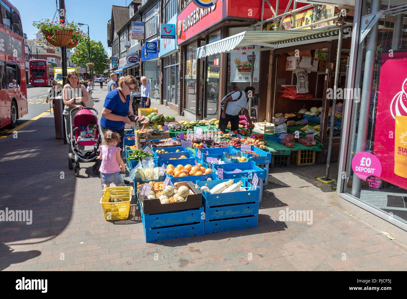 A woman and small child look at a display of vegetables and fruit ...
