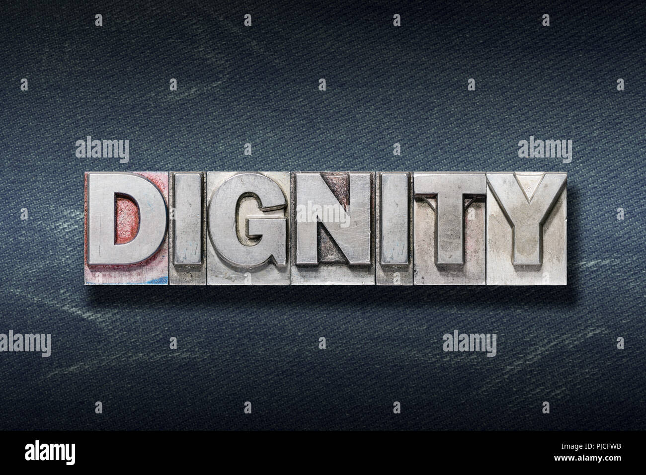 dignity word made from metallic letterpress on dark jeans background ...