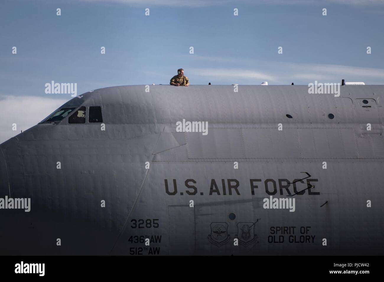 An Airman looks out onto the flightline on top of a C-5 Galaxy during ...