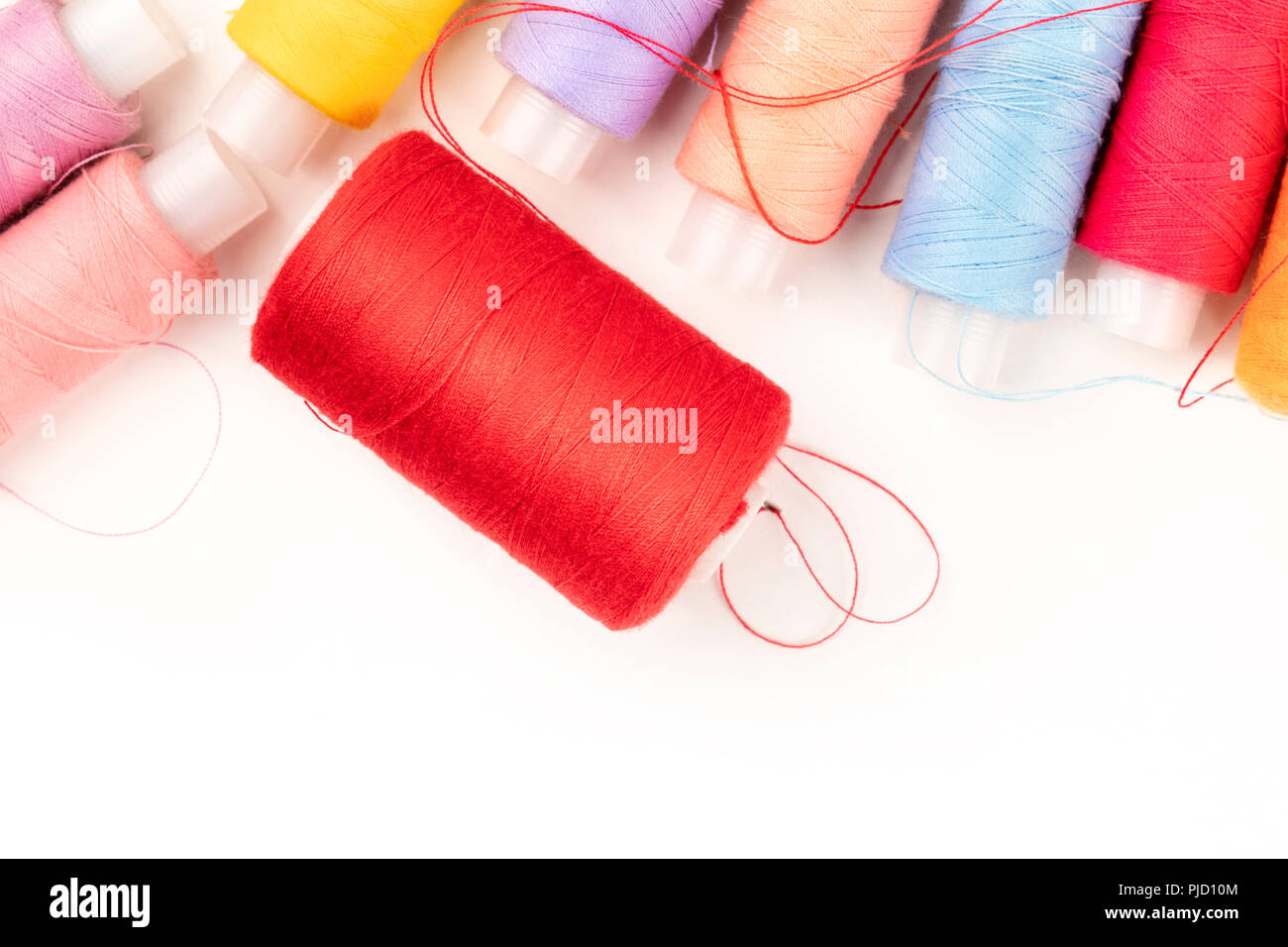 An overhead photo of vibrant threads of various colors on a white ...