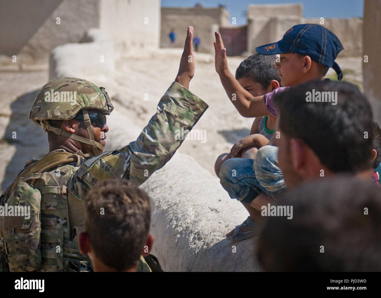 A U.S. Soldier high-fives a child during a patrol in their village ...
